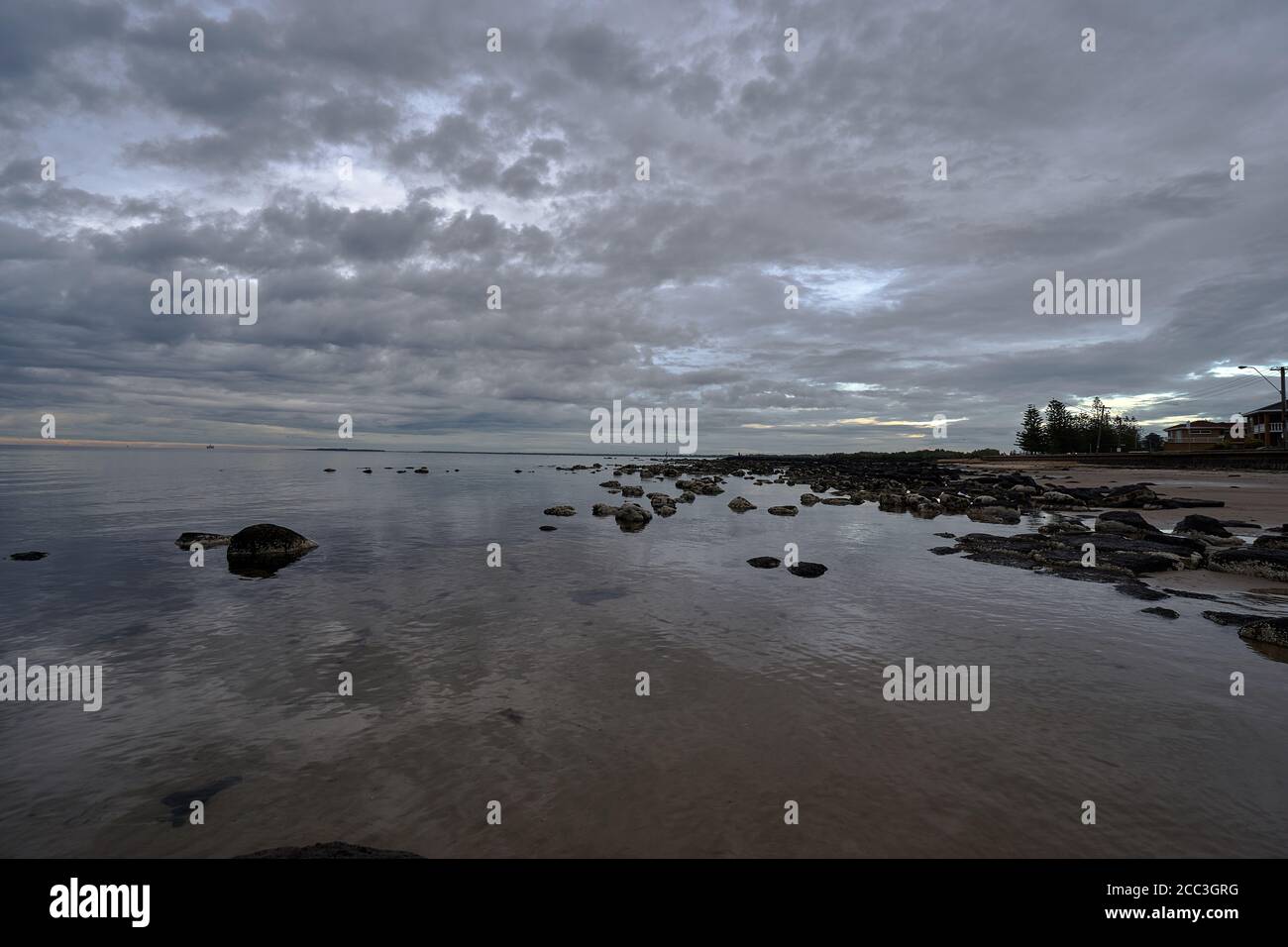 quiet flat seas under a dramatic brooding sky Stock Photo - Alamy