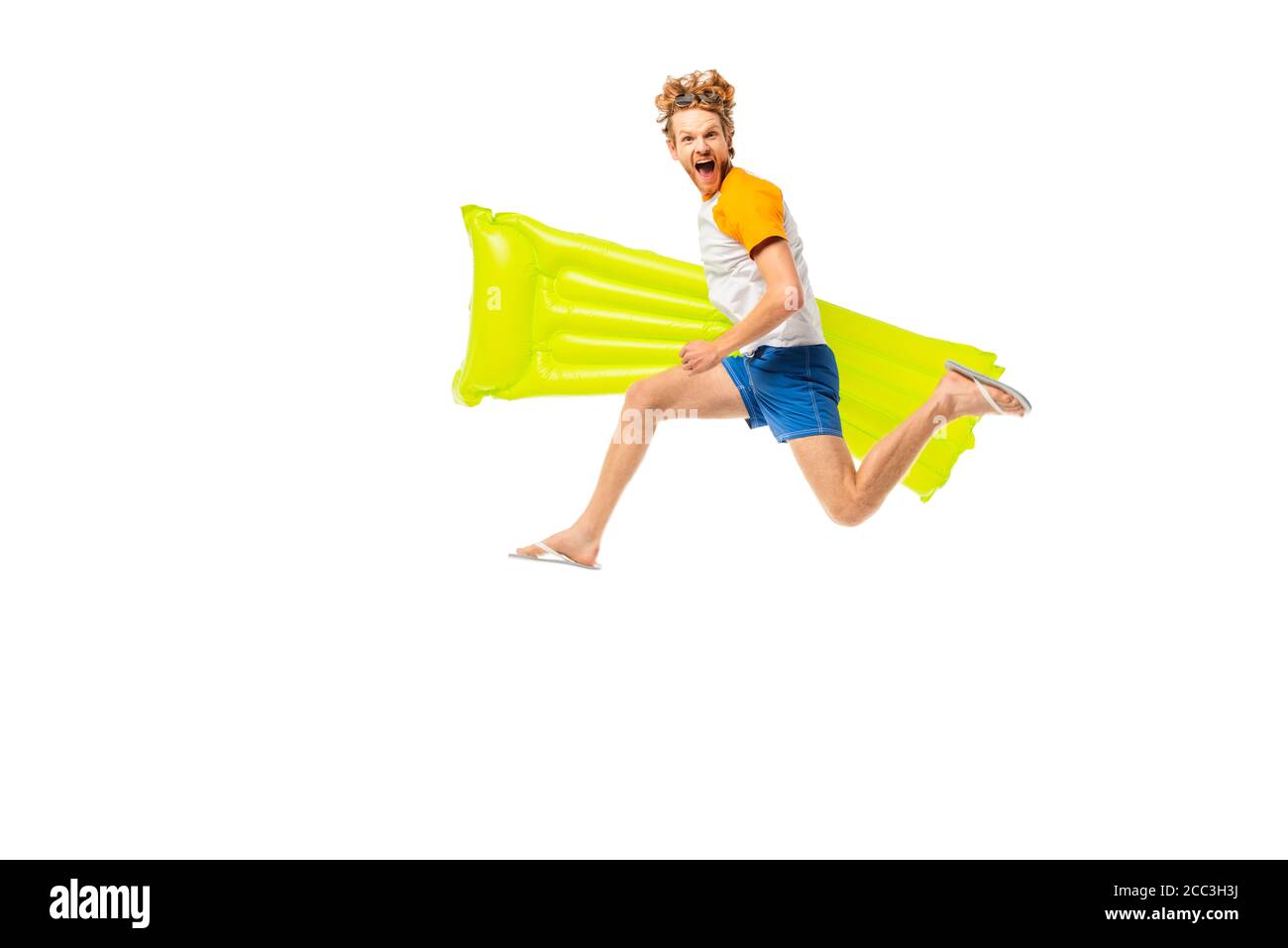 Side view of excited man holding inflatable mattress while jumping ...
