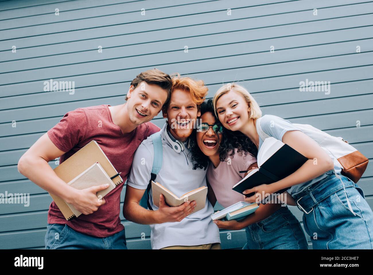 excited multicultural students looking at camera while holding ...