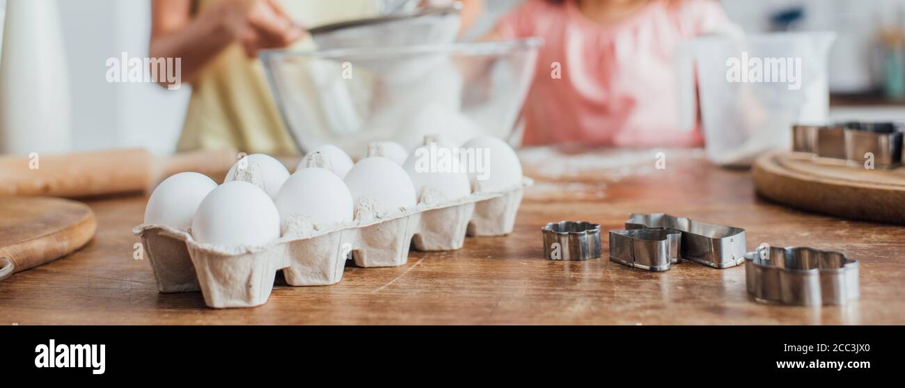 selective focus of chicken eggs and cookie cutters near woman and child ...