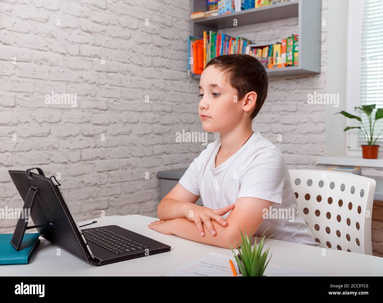 Schoolboy boy studies at home and does school homework. Homeschooling ...