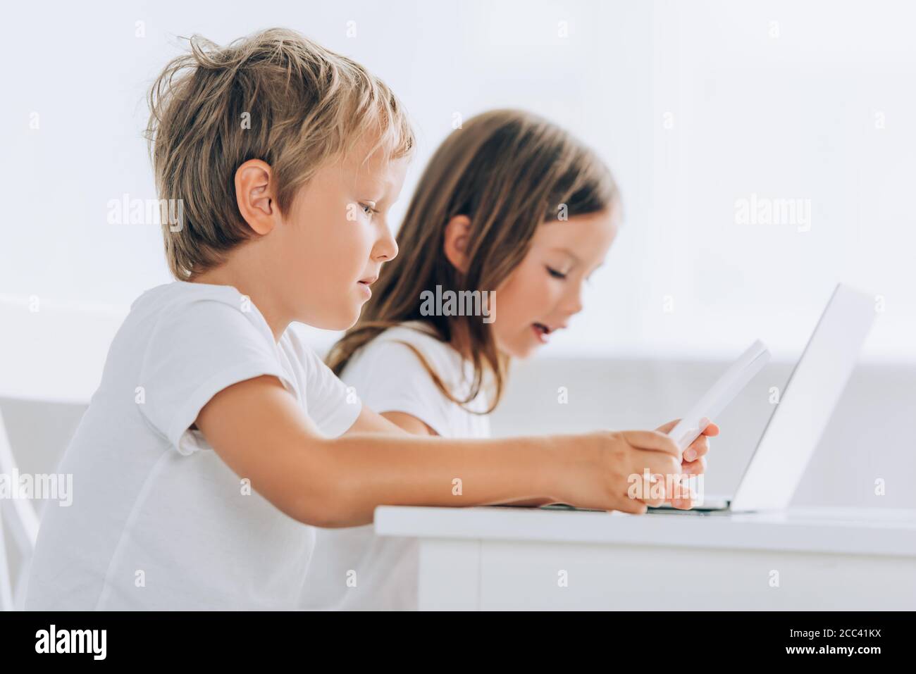 selective focus of concentrated boy and girl using laptops at home ...
