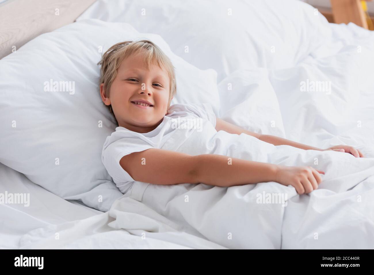 awakened boy looking at camera while lying in bed Stock Photo - Alamy