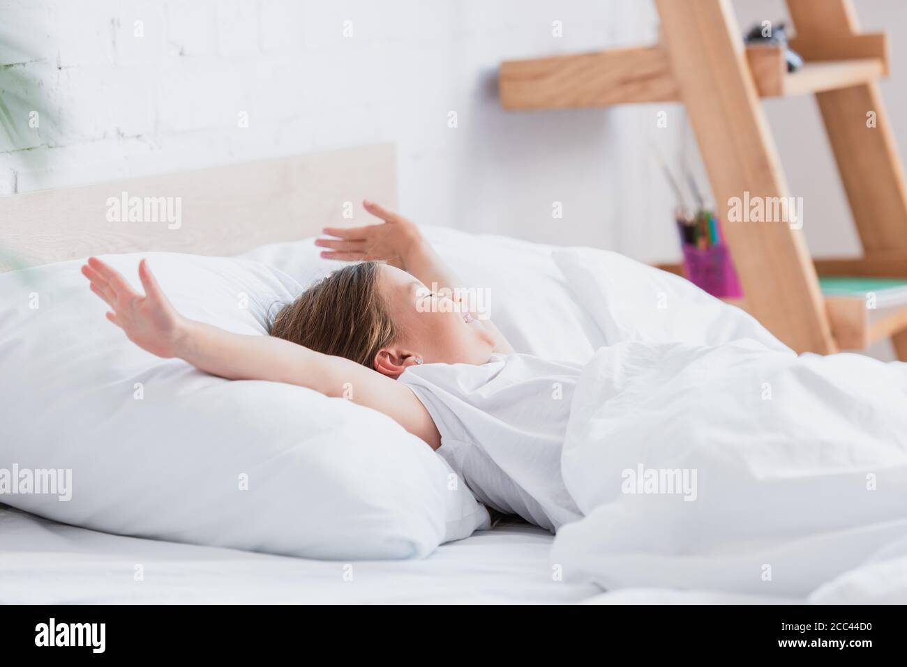 awakened girl stretching while lying in bed and looking away Stock ...