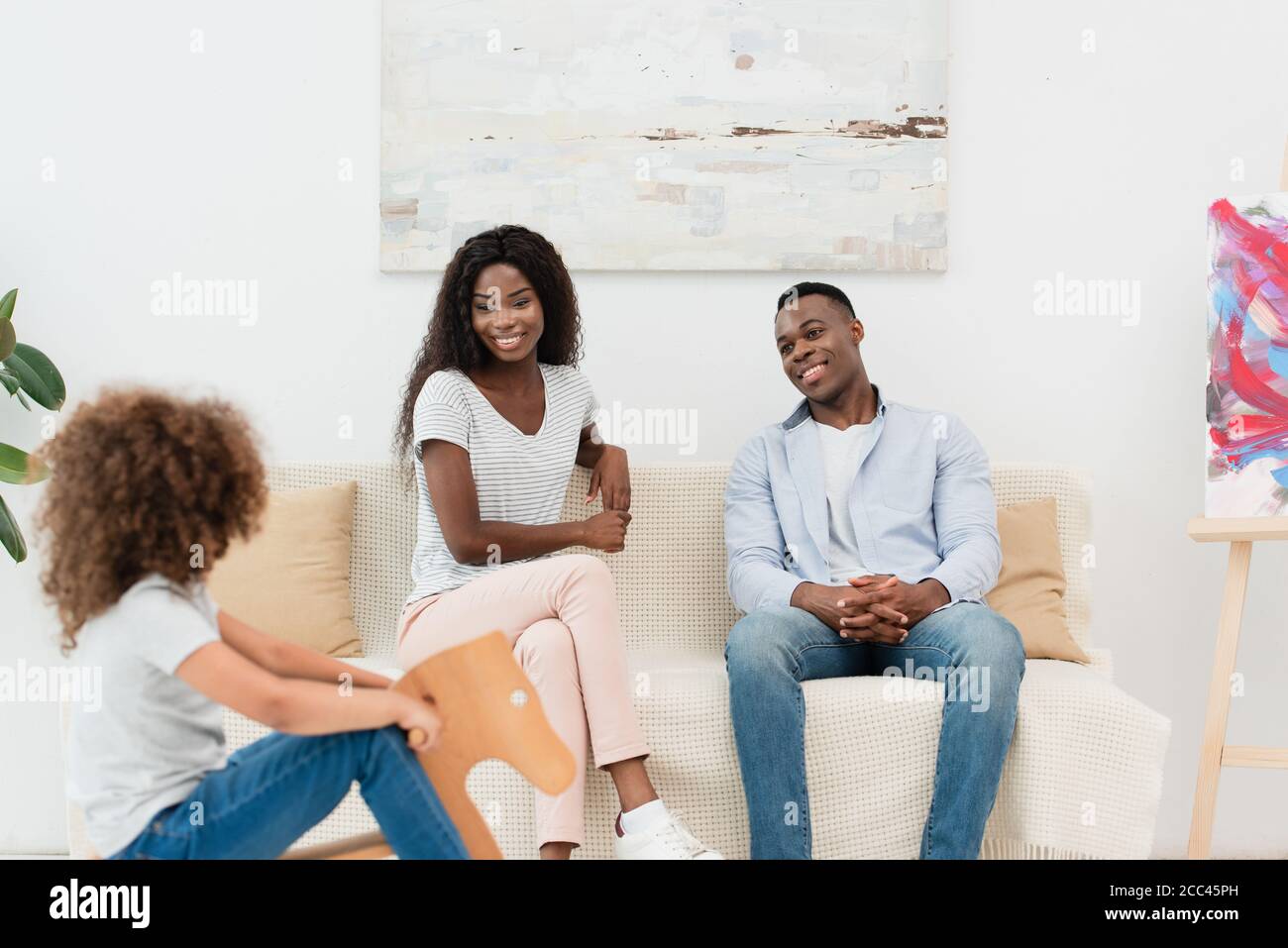 selective focus of african american parents looking at kid sitting on ...