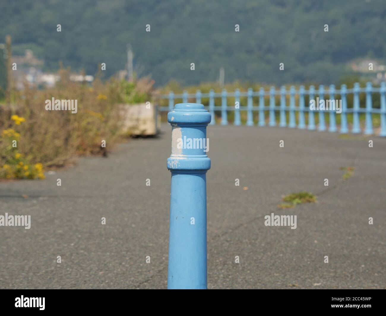 Single blue bollard outdoors with a blue fence in the background during ...