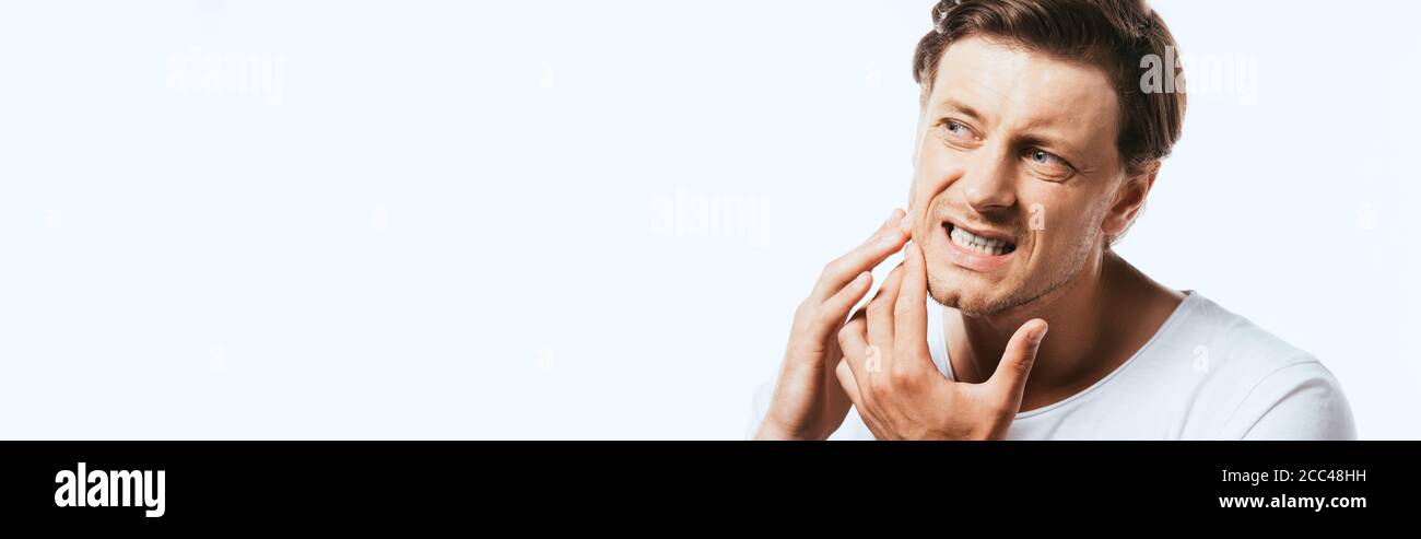 Panoramic orientation of displeased man touching skin on cheek isolated ...