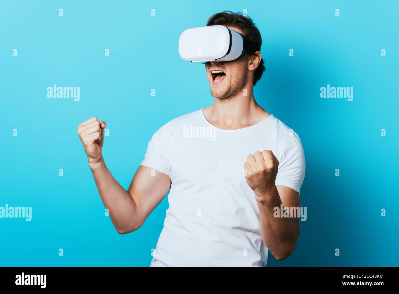 Man in vr headset showing yeah gesture on blue background Stock Photo ...