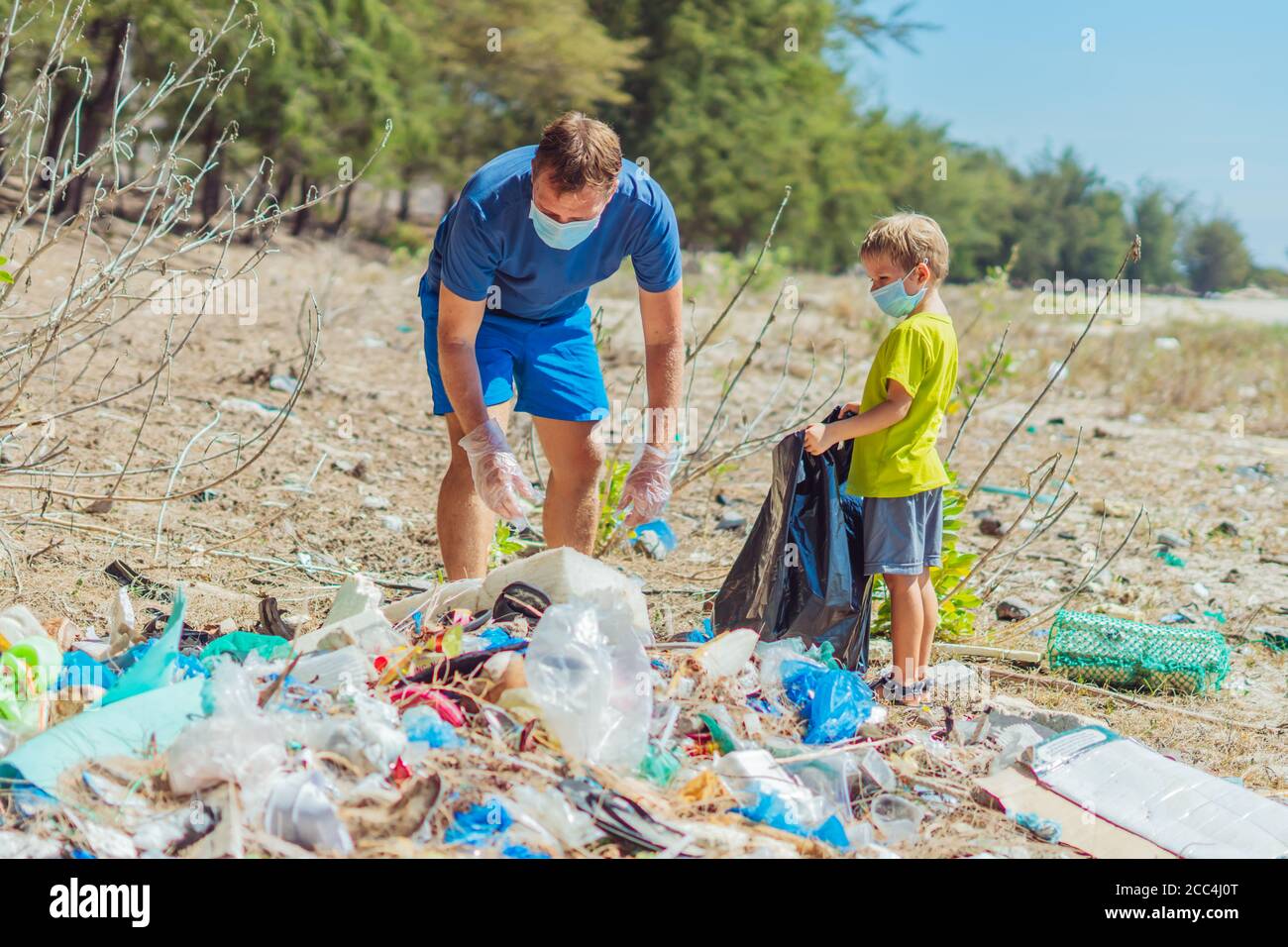 Volunteers in blue face mask. Father, son pick up garbage which pollute ...