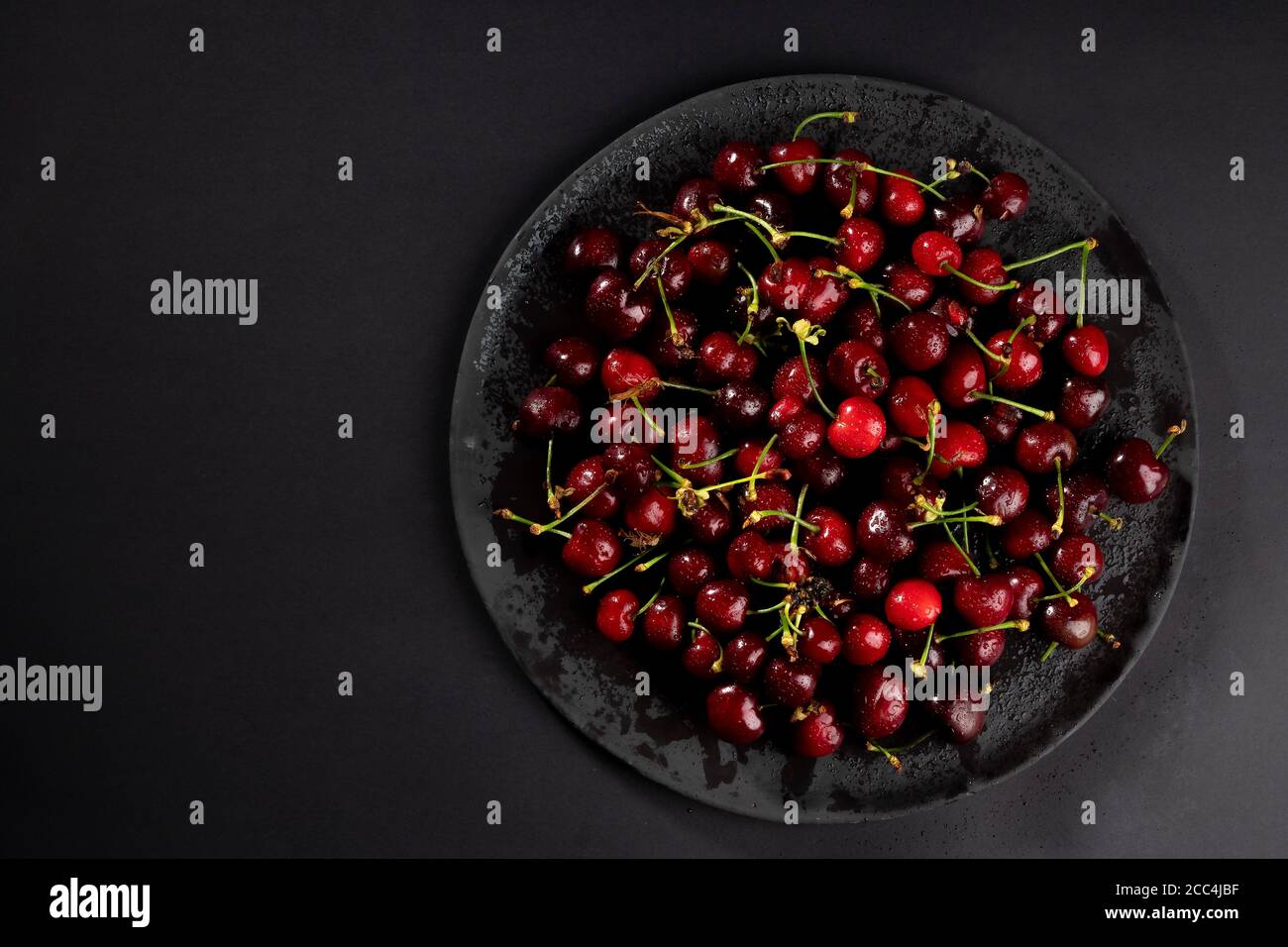 Top view on fresh, wet, dark cherries. Water drops on bright shiny dark ...