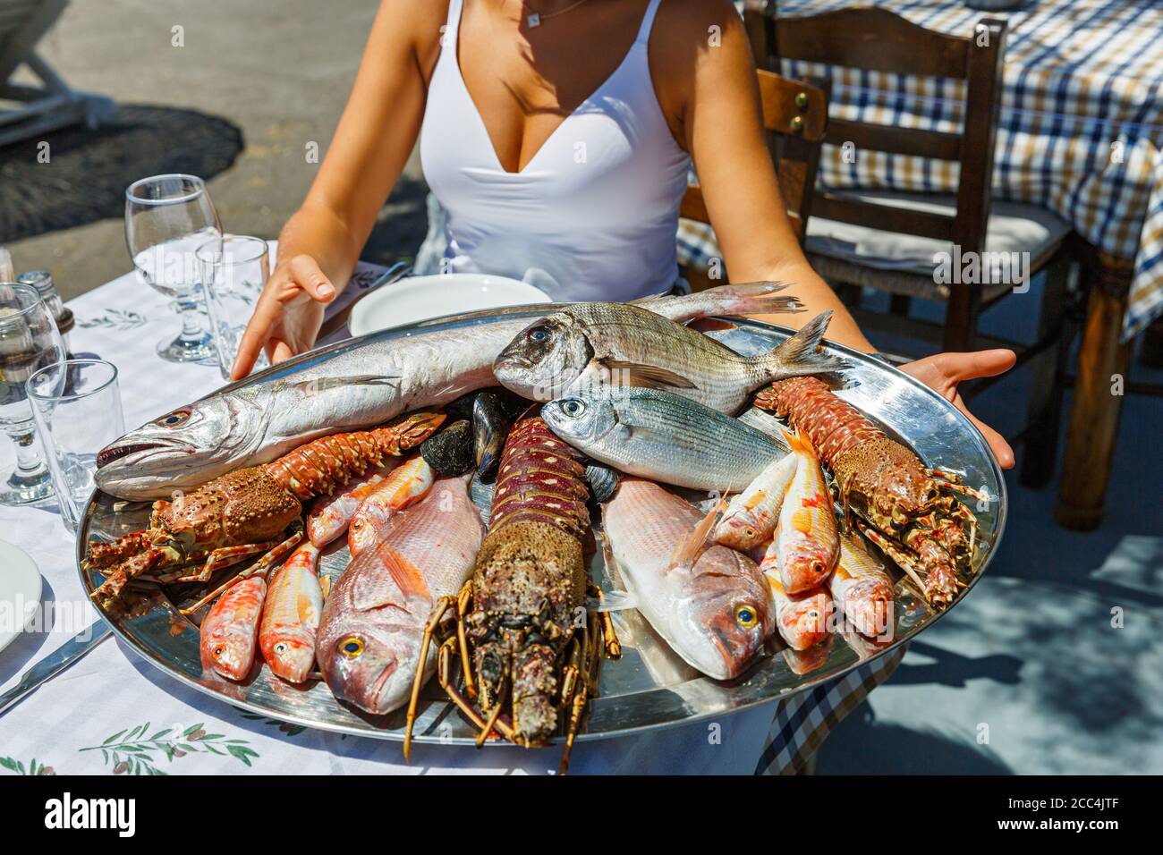 Beautiful, young woman chooses fresh fish in a beach restaurant for ...