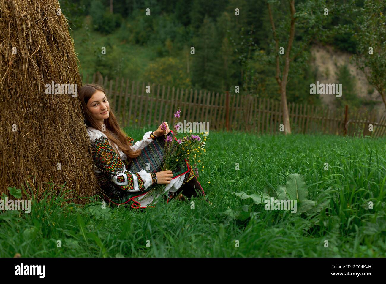 girl with loose hair with a bouquet of wildflowers sits with her back ...