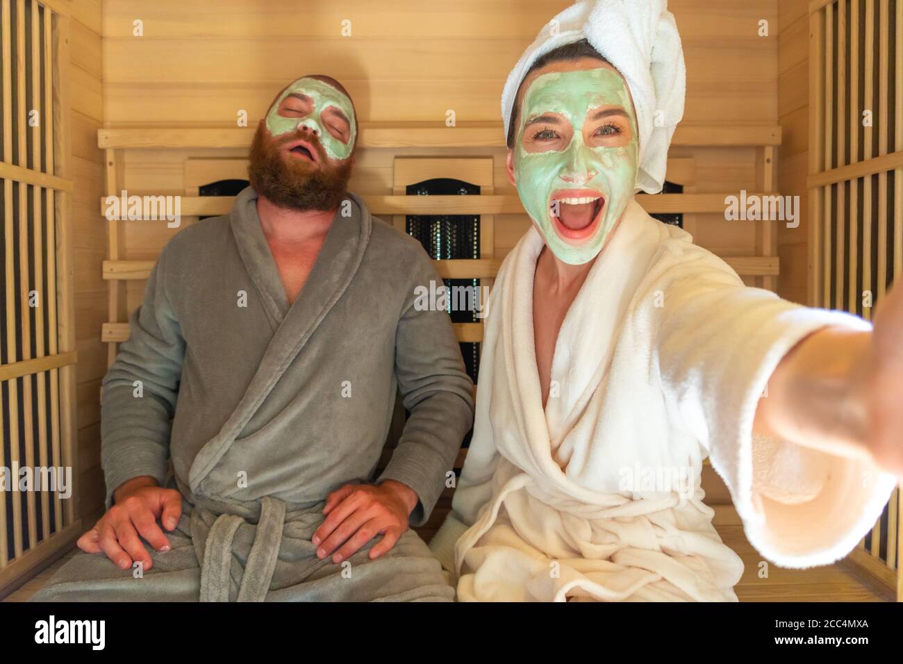 A young funny couple having relax SPA day in sauna, a woman making ...