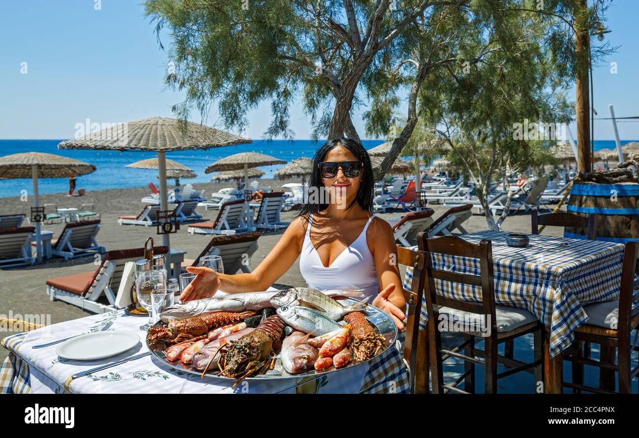Beautiful, young woman chooses fresh fish in a beach restaurant for ...