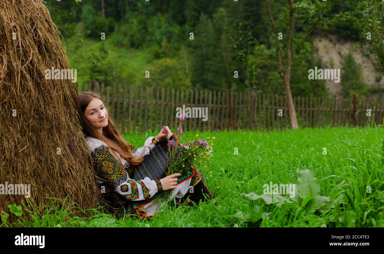 girl with loose hair with a bouquet of wildflowers sits with her back ...
