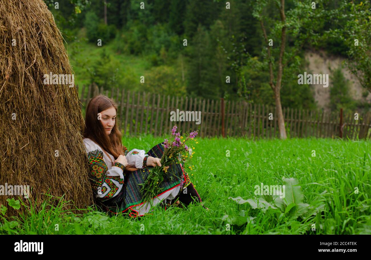 girl with loose hair with a bouquet of wildflowers sits with her back ...