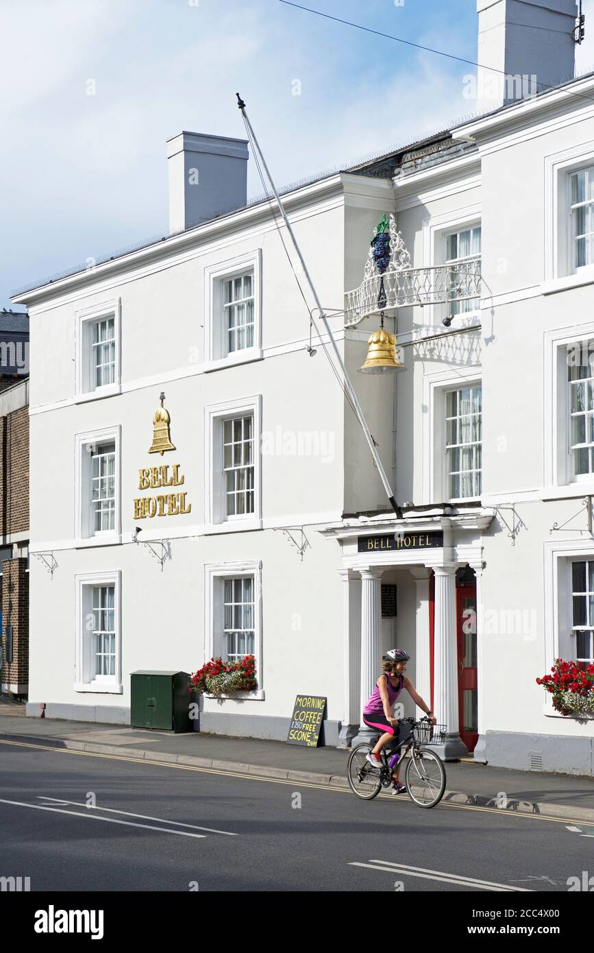Young woman cycling past the Bell Hotel, Market Place, Driffield, East ...