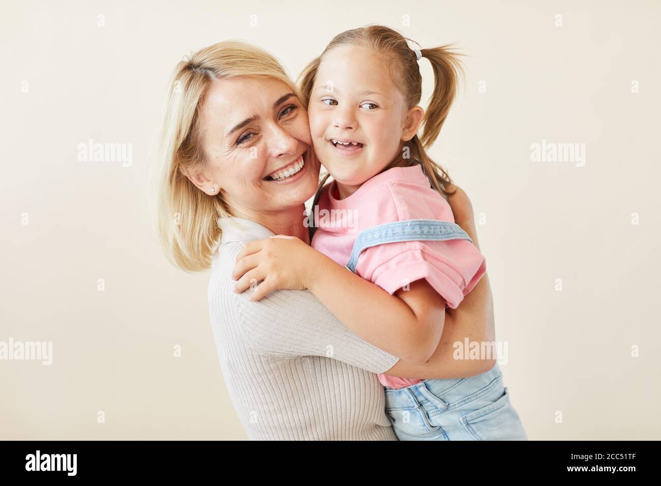 Portrait of happy mother embracing her daughter with down syndrome ...