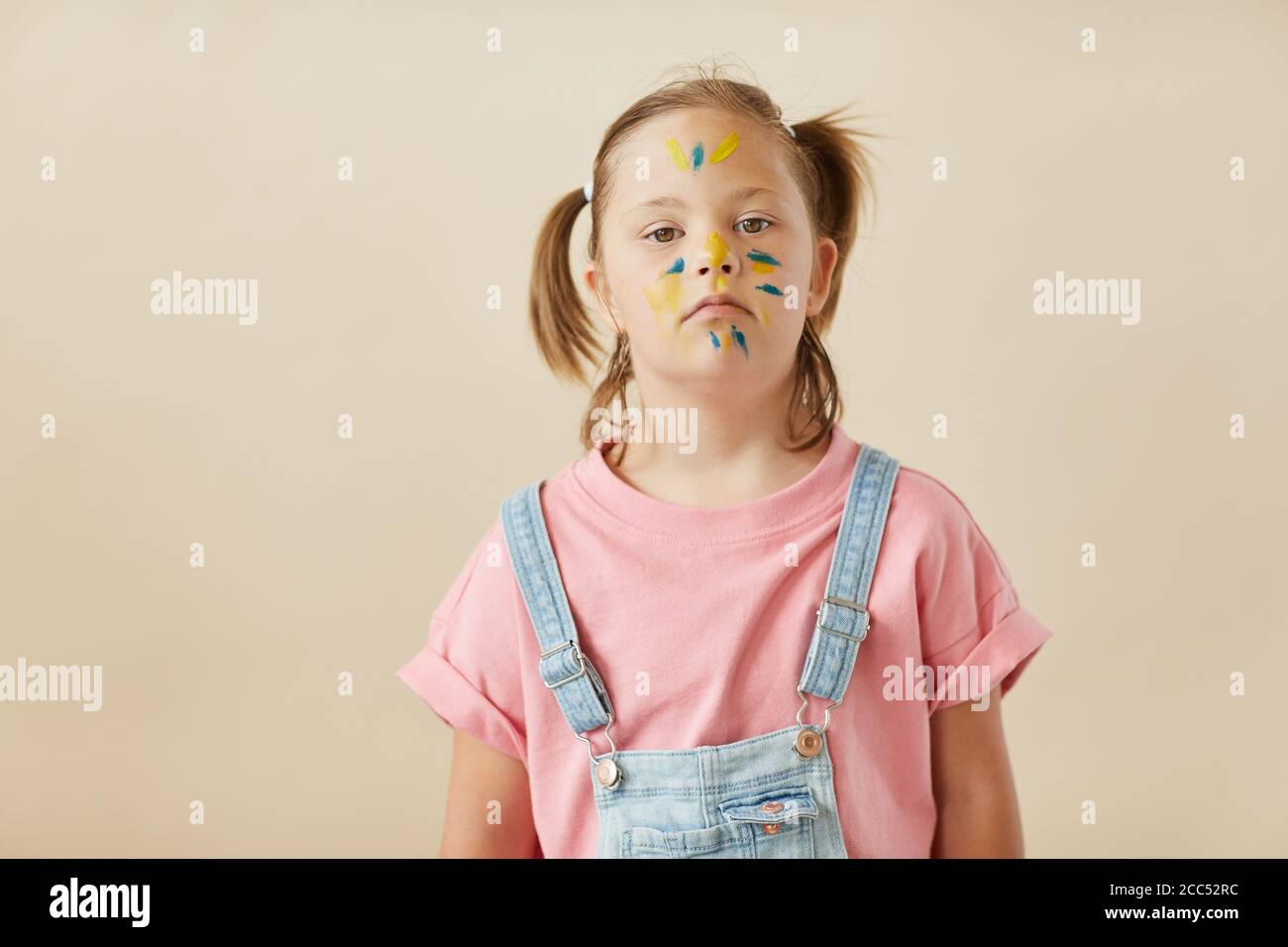 Portrait of down syndrome child with painted face looking at camera ...