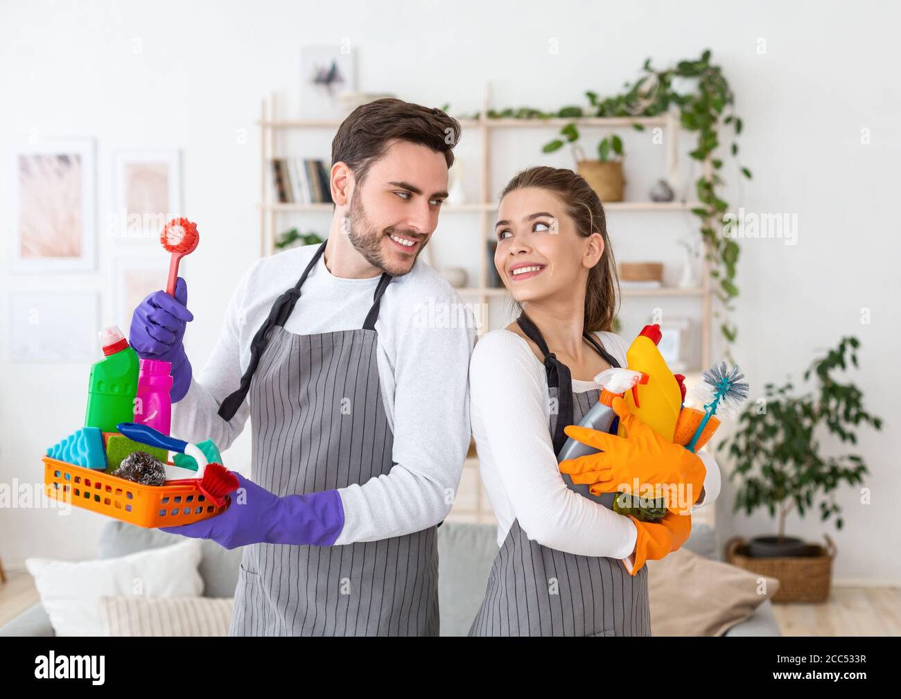 Cleaning supplies for cleaning. Smiling husband and wife look at each ...