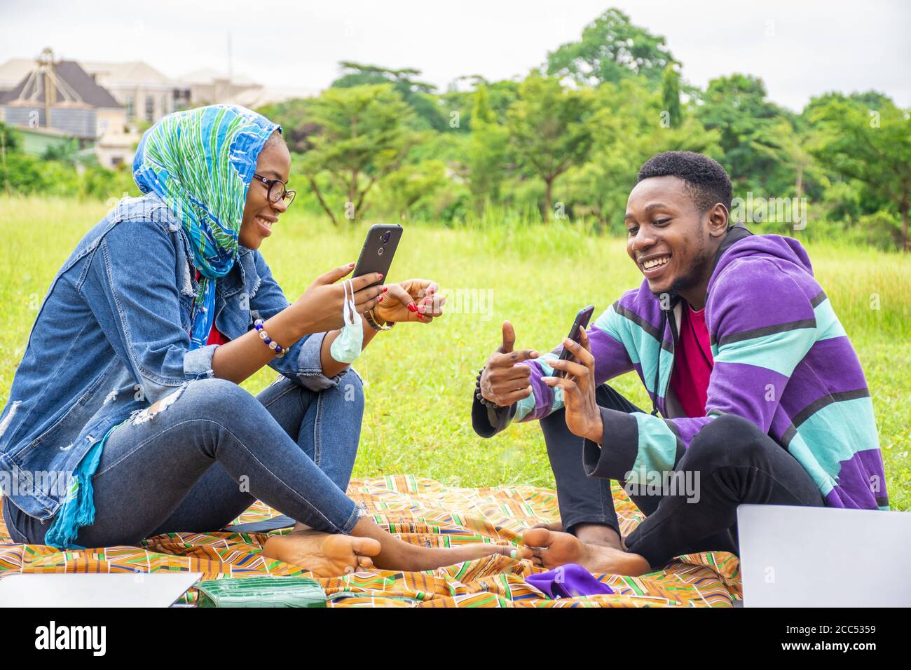 Shallow focus of two young African friends hanging out at a park while ...