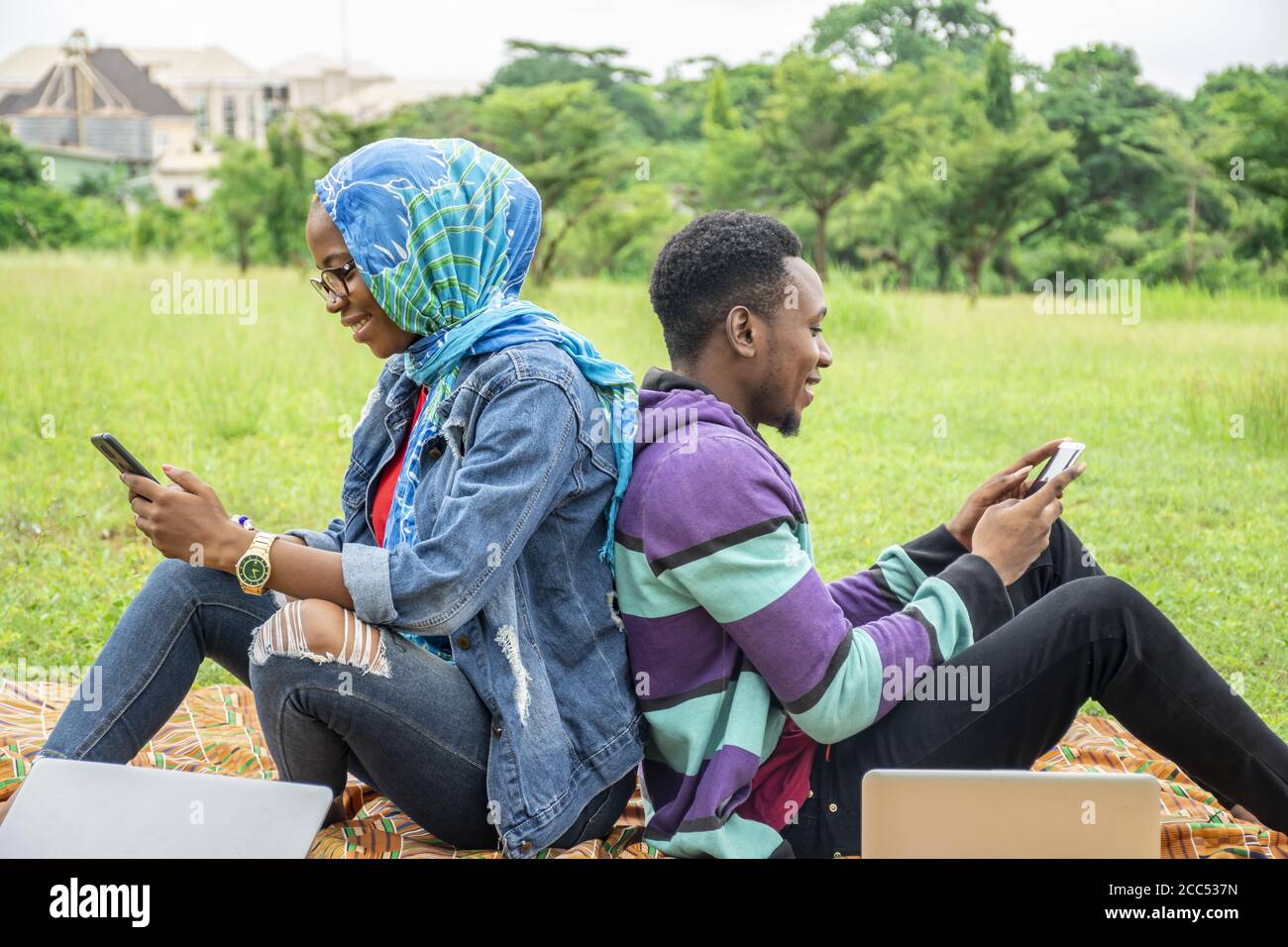 Shallow focus of two young African friends hanging out at a park while ...