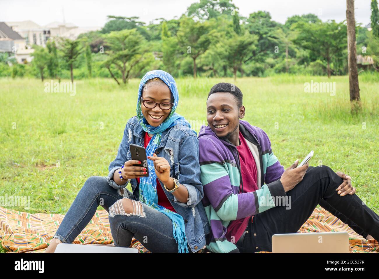 Shallow focus of two young African friends hanging out at a park while ...