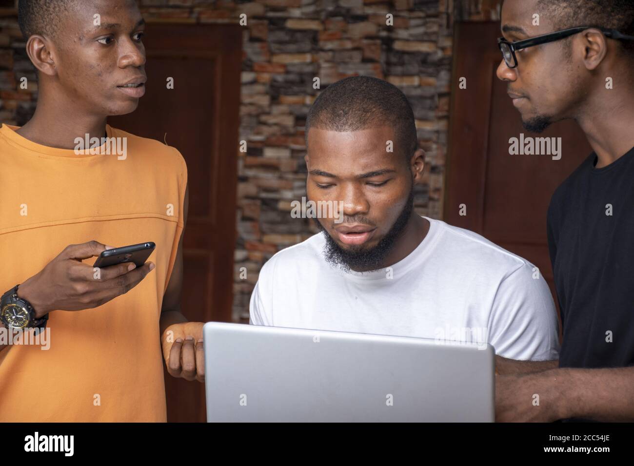 Group of young African males discussing a project while using their ...