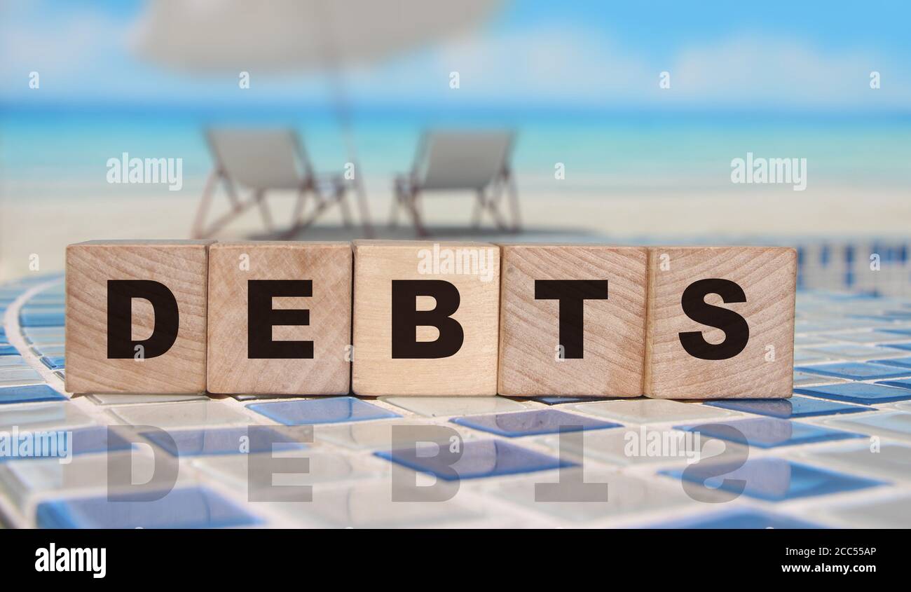 Debts on wooden cubes on relaxed beach background. Financial concept ...