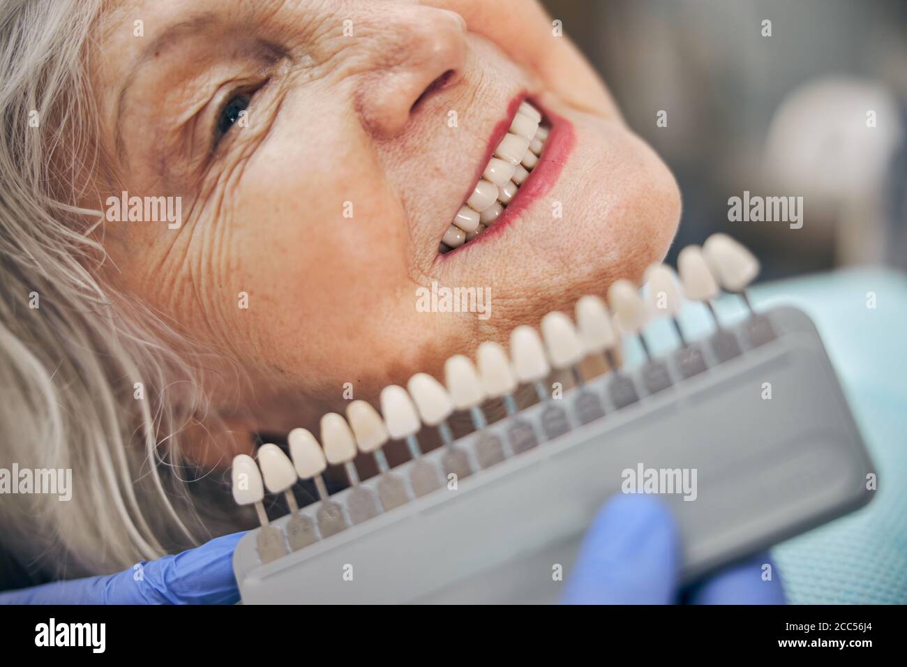 Dentist selecting patient teeth color with palette in clinic Stock ...