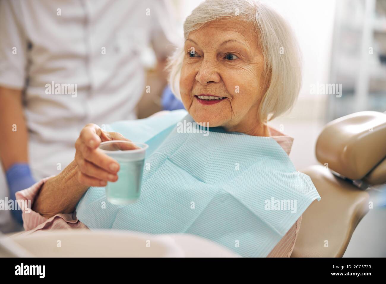 Smiling good looking female holding cup with water Stock Photo - Alamy