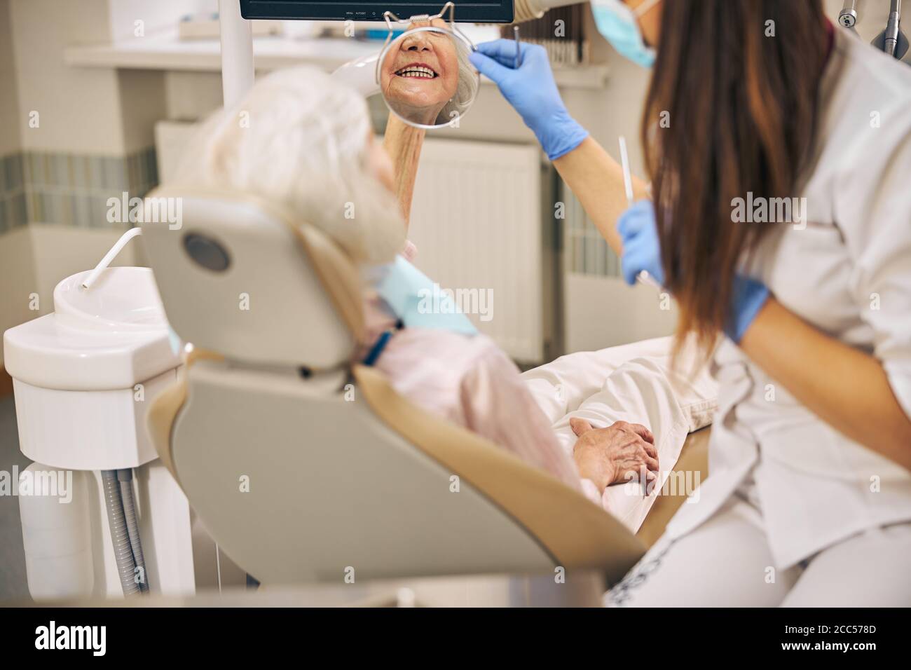 Female dentist examining teeth using mirror in dental clinic Stock ...