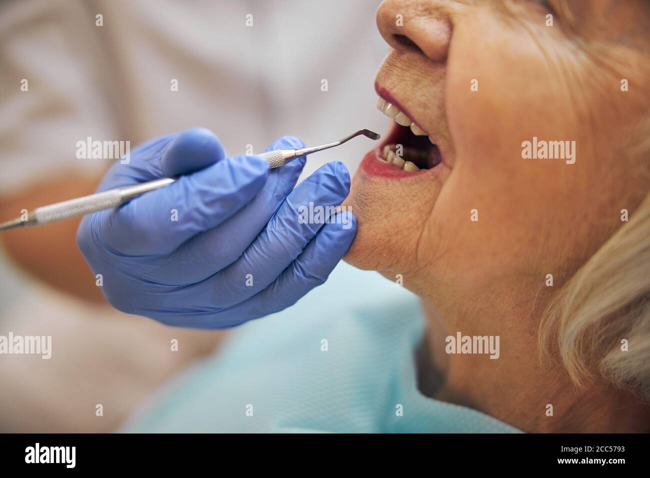 Female patient with open mouth examining dental inspection at dentist ...