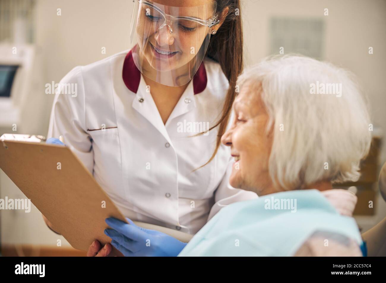 Happy smiling patient of dental clinic looking at the clipboard Stock ...