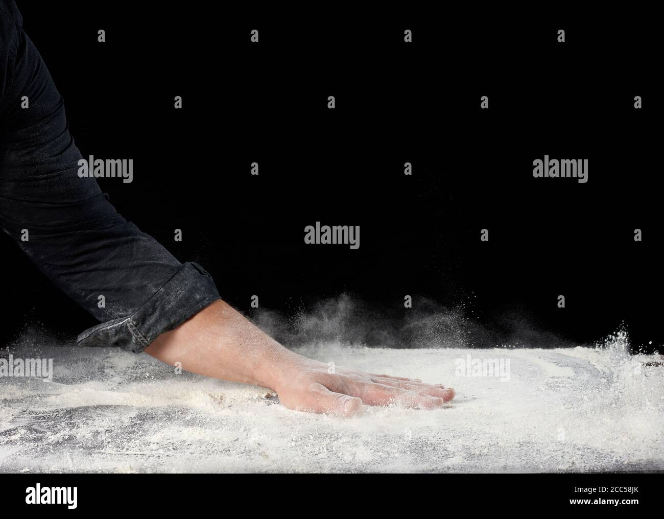 chef in black uniform sprinkles white wheat flour in different ...
