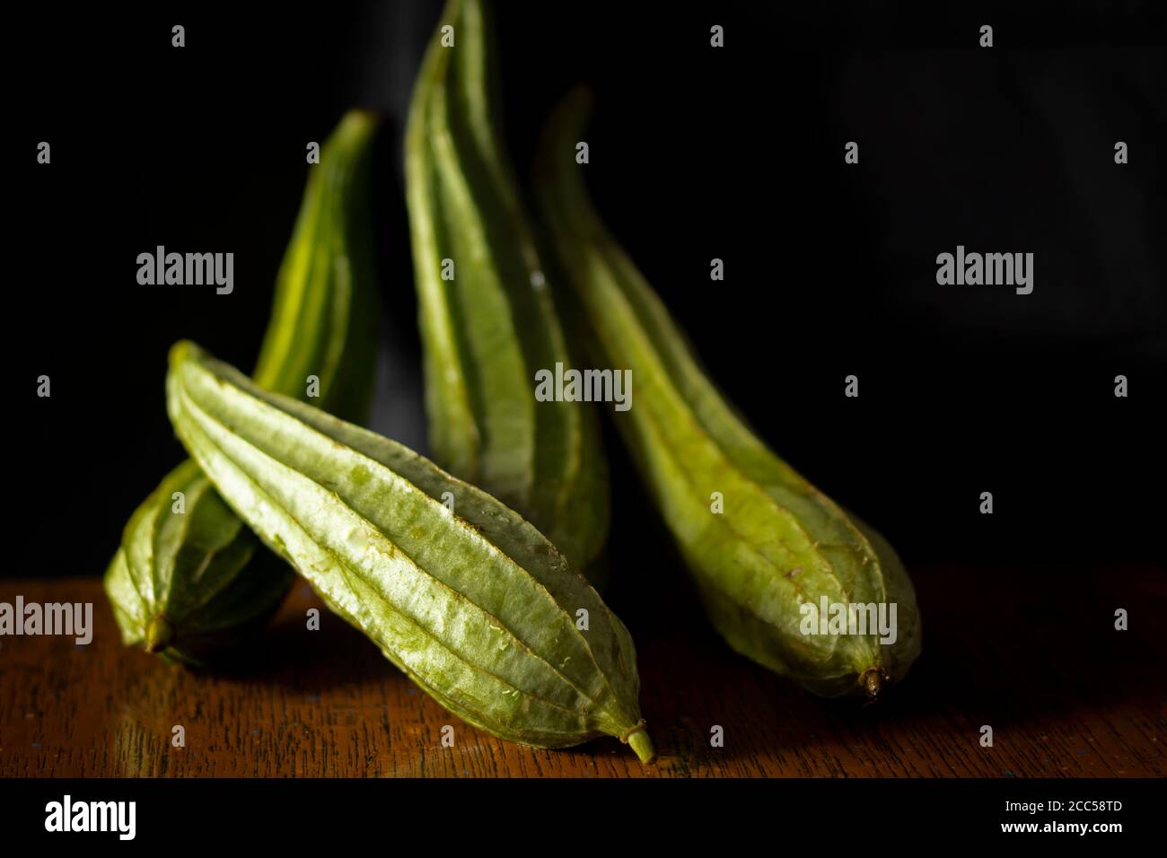 group of green fresh ridged gourd or jhinga on table black background ...