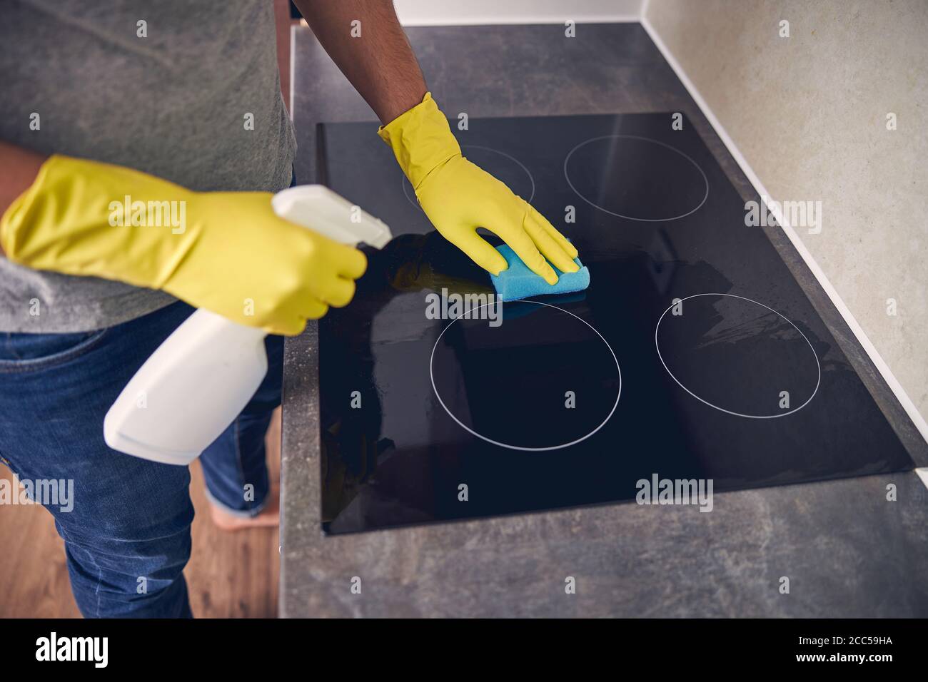 Cleaning kichen cooker with spray and yellow duster Stock Photo - Alamy