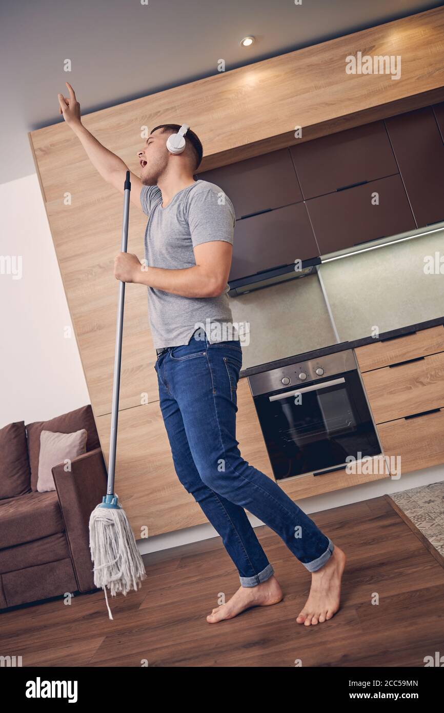 Young man singing while cleaning living room Stock Photo - Alamy