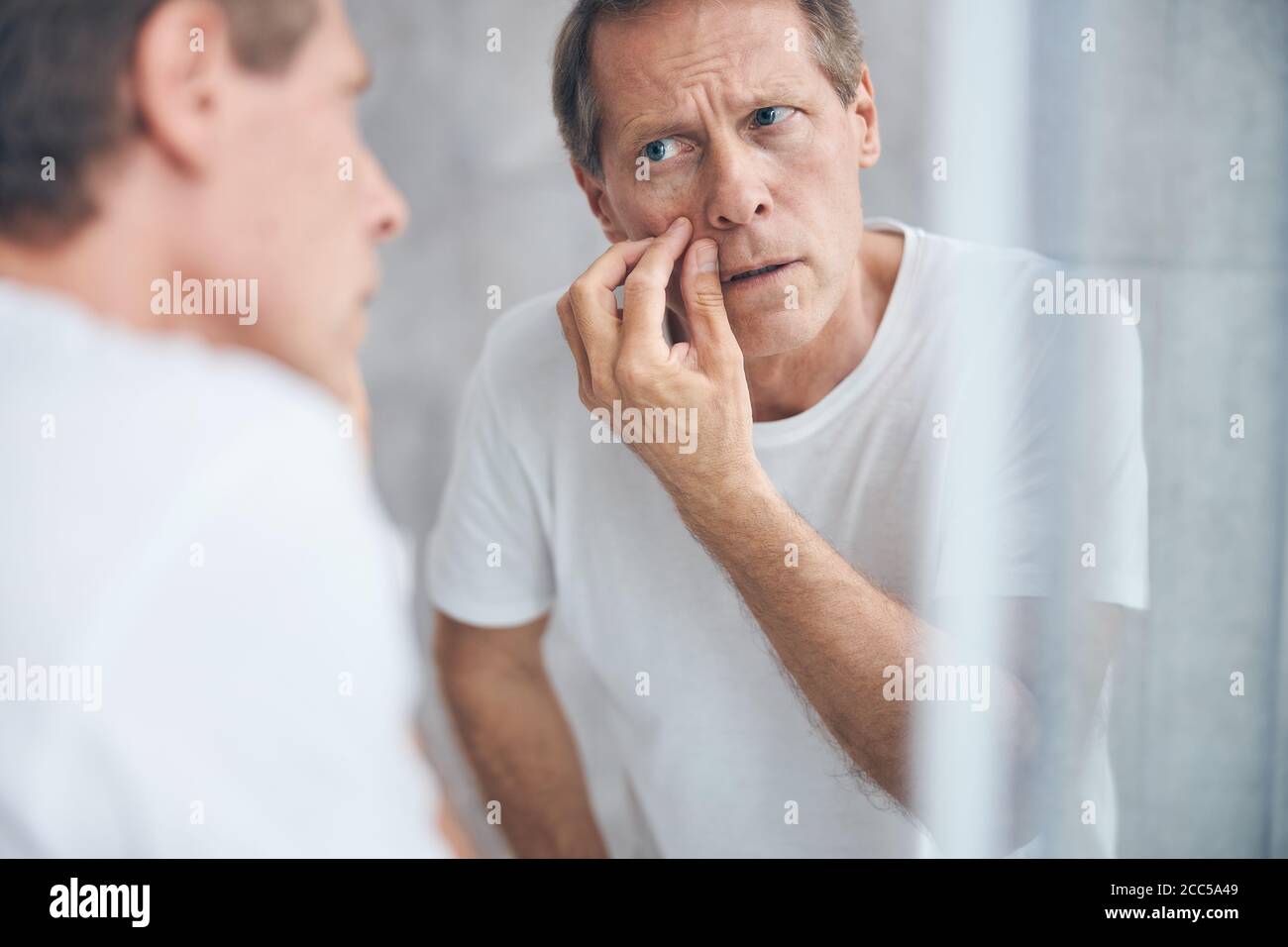 Serious man looking intently at his reflection Stock Photo - Alamy