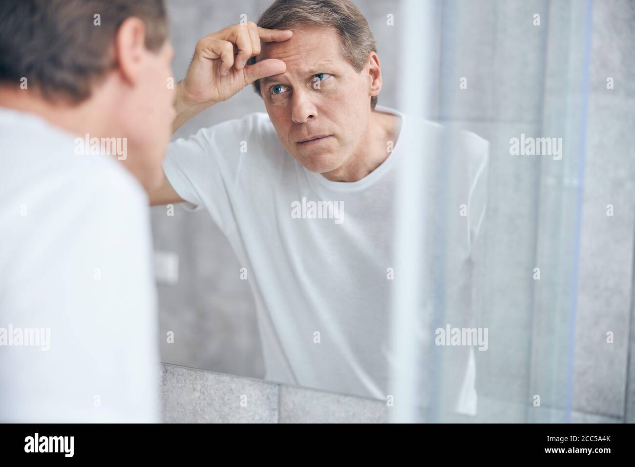 Concentrated man staring at his facial skin Stock Photo - Alamy