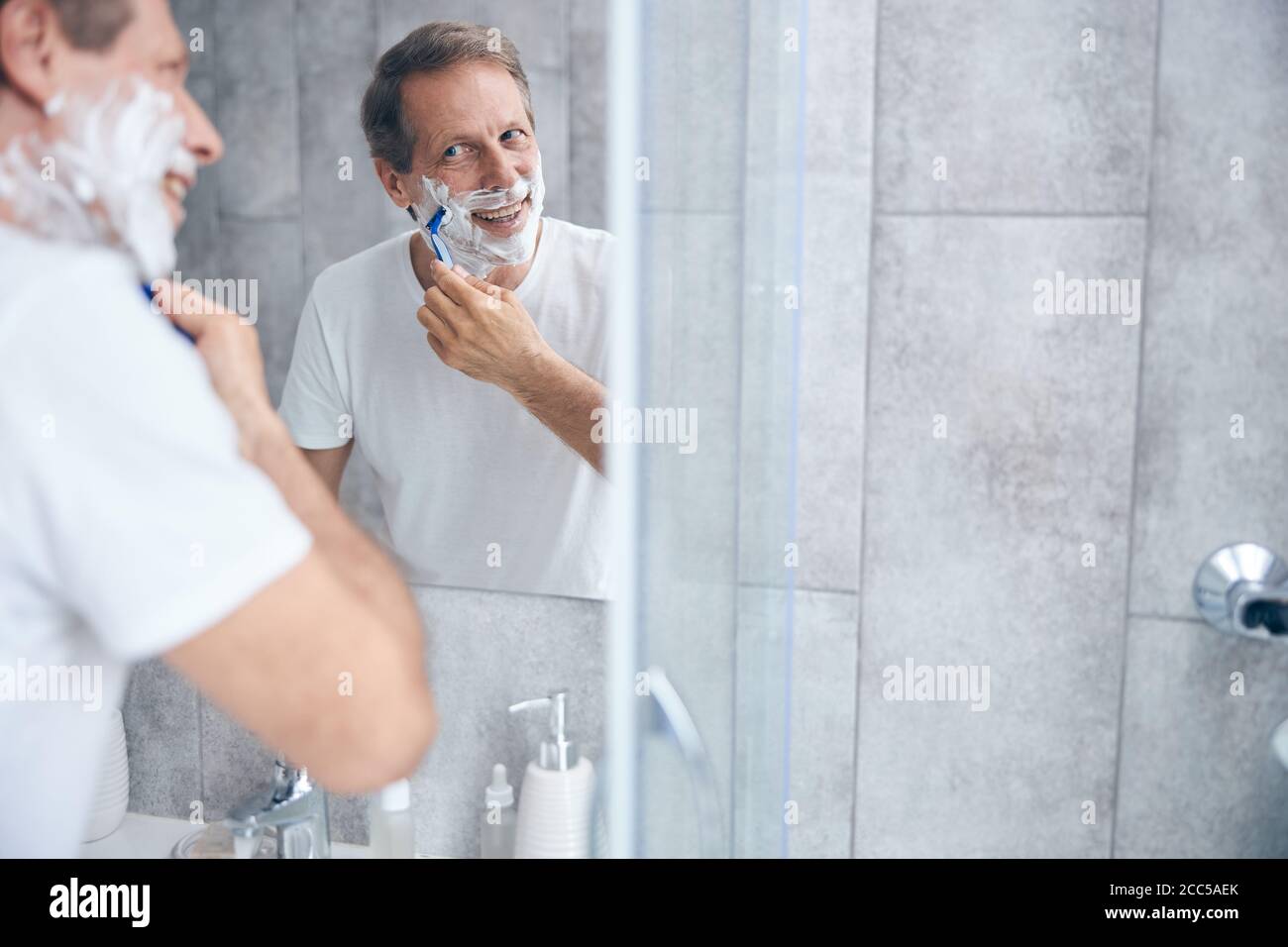 Pleased male shaving himself in the bathroom Stock Photo - Alamy