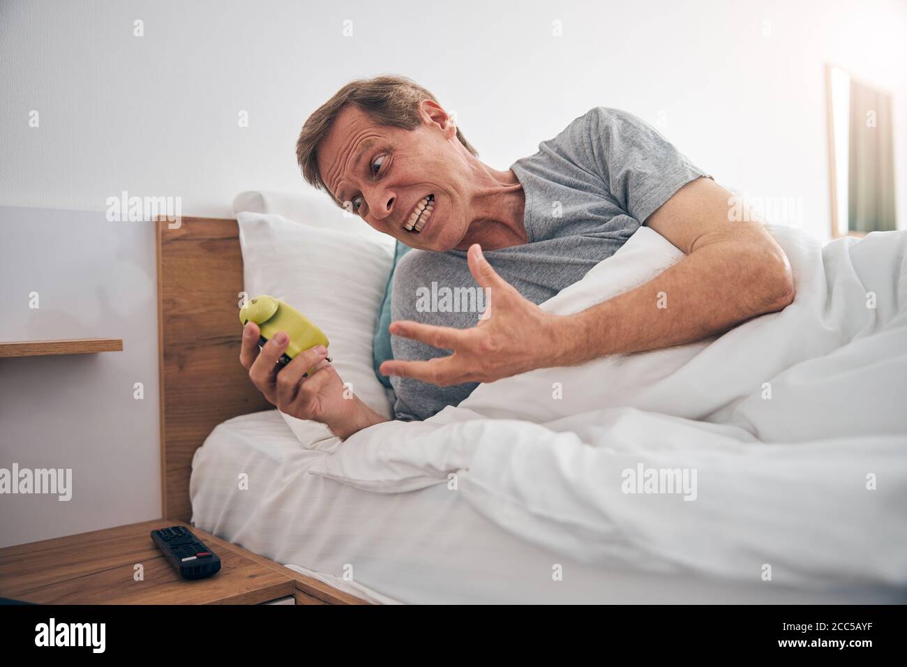 Angry male person shouting at alarm clock Stock Photo - Alamy