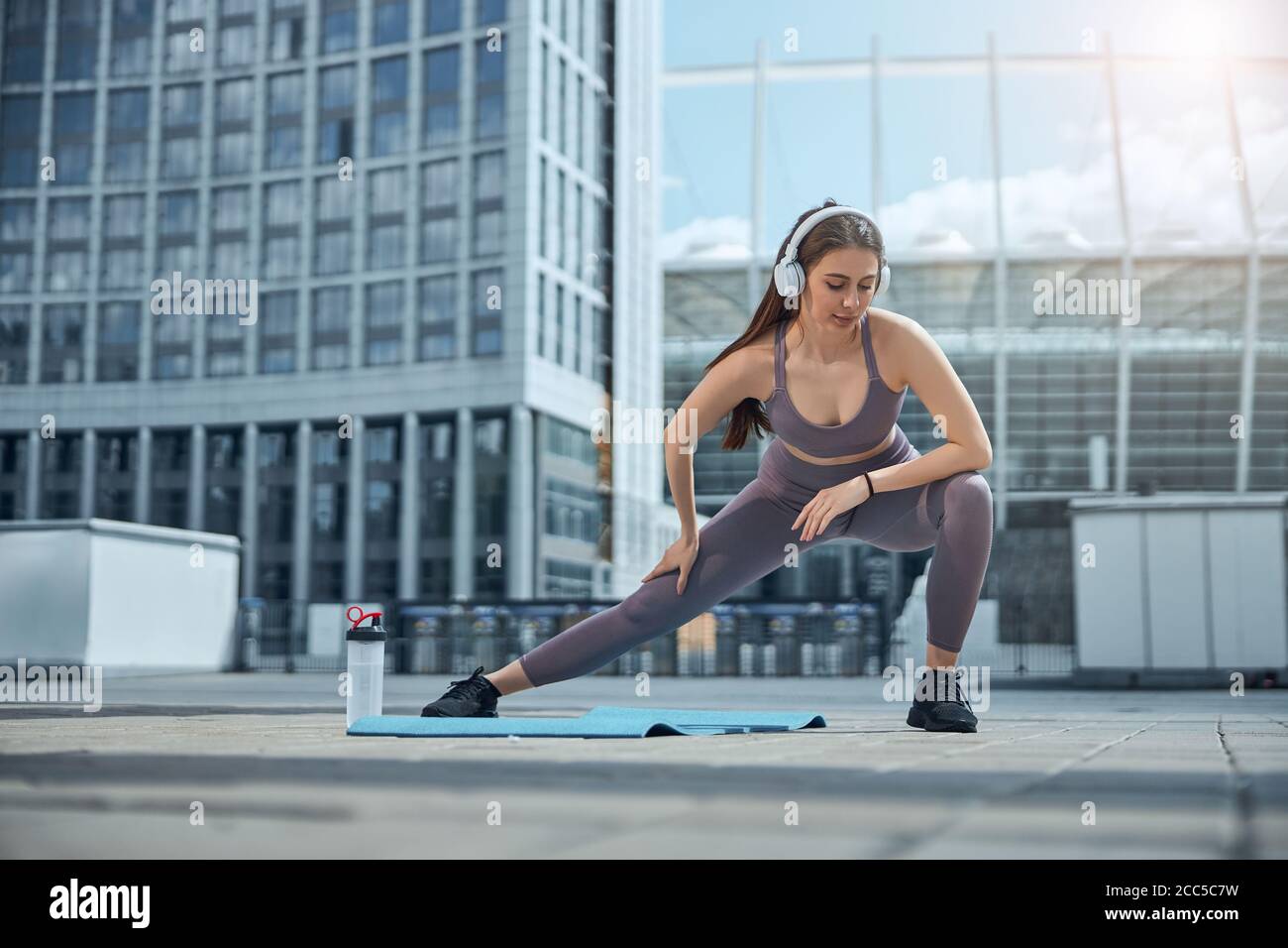 Sporty young woman doing leg stretches outside Stock Photo - Alamy