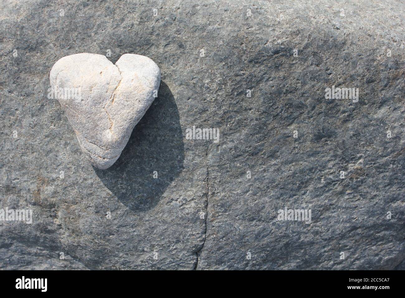 White heart shaped stone on grey rock hi-res stock photography and ...