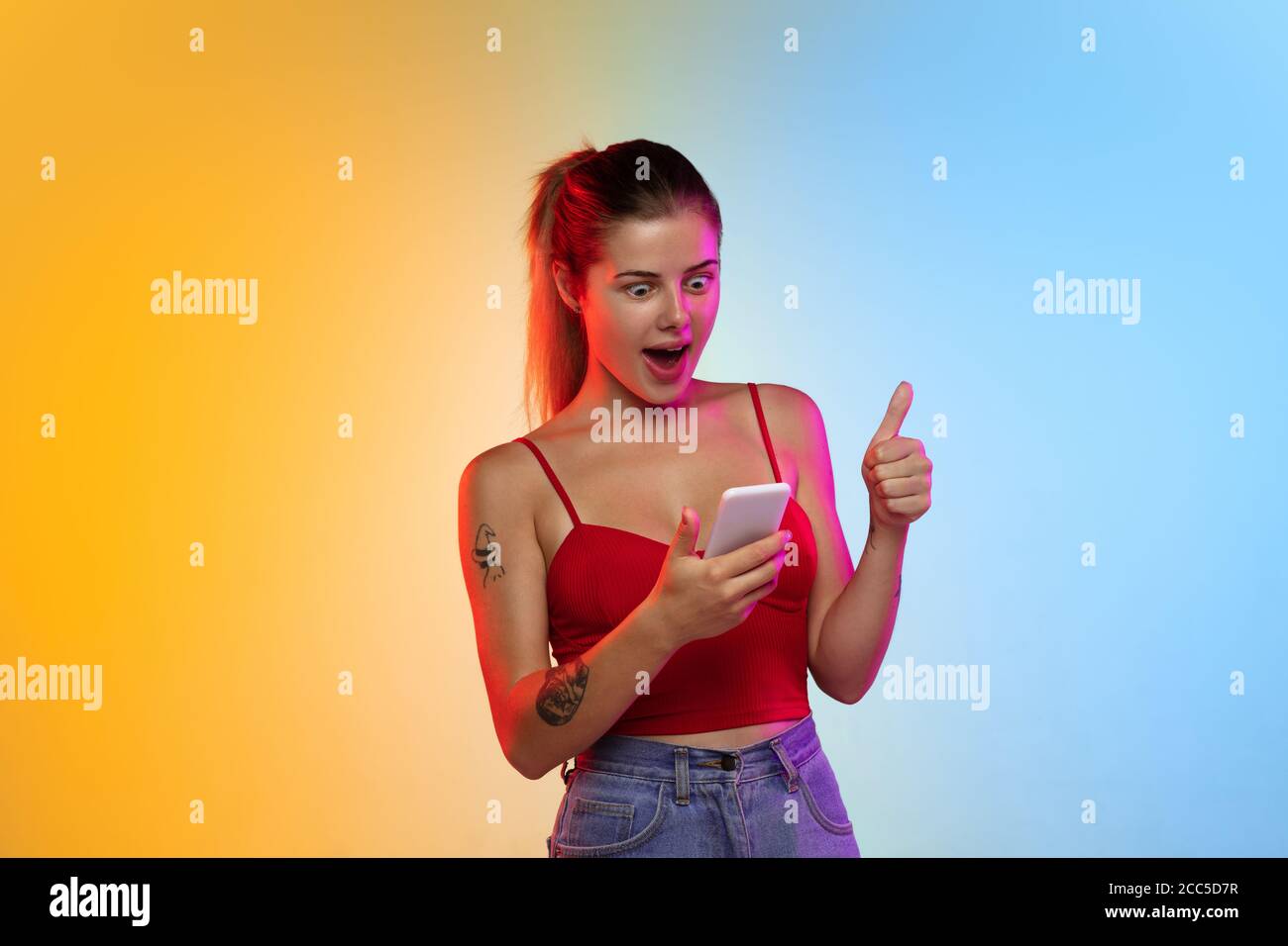 Scrolling phone. Caucasian young woman's portrait on gradient studio ...