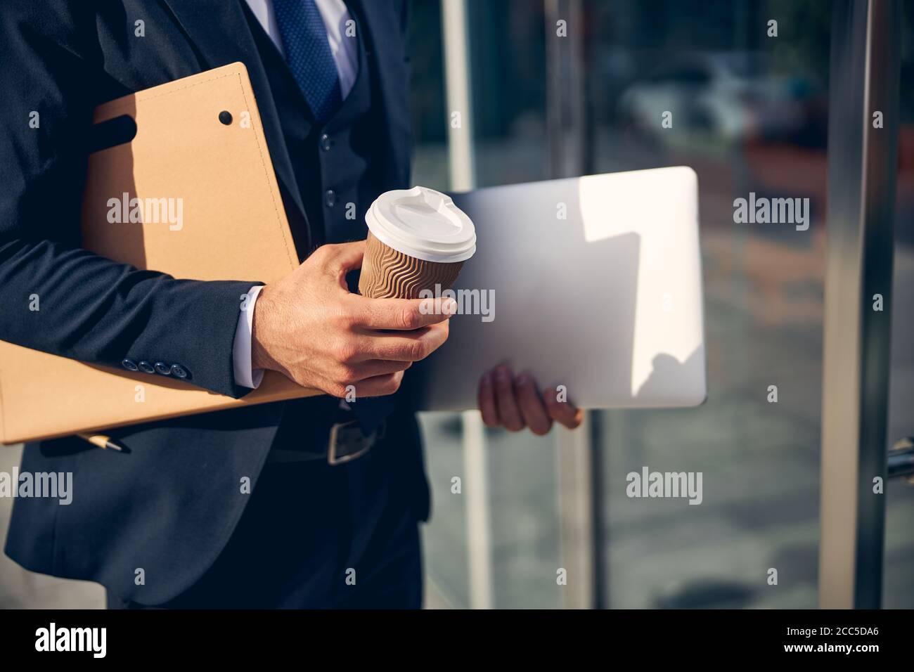 Man holding papers and drink in hands Stock Photo - Alamy