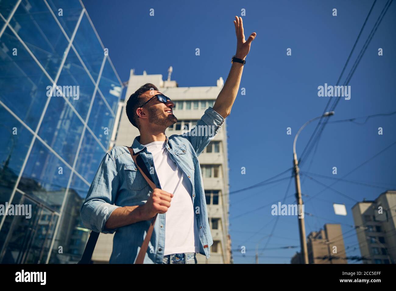 Handsome young man covering his face from sun Stock Photo - Alamy