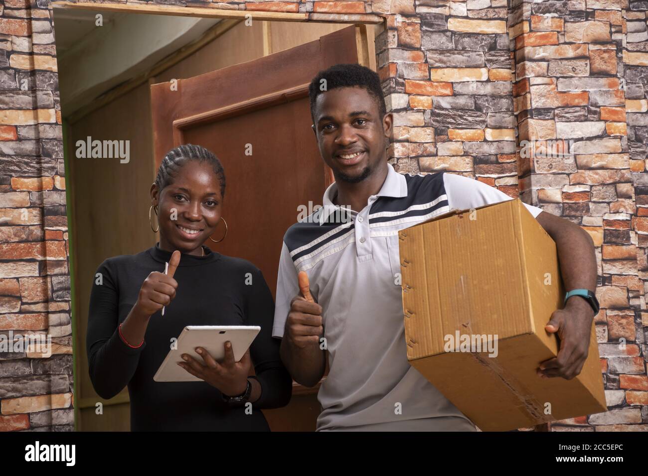 Satisfied African female receiving a parcel from the courier Stock ...