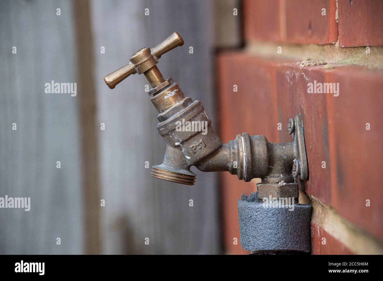 Isolated outdoor tap on the side of a brick house, ready for a hose ...