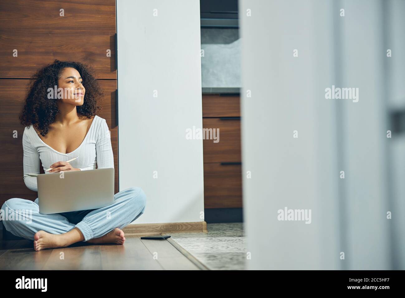 Female with a computer on her knees looking away Stock Photo - Alamy